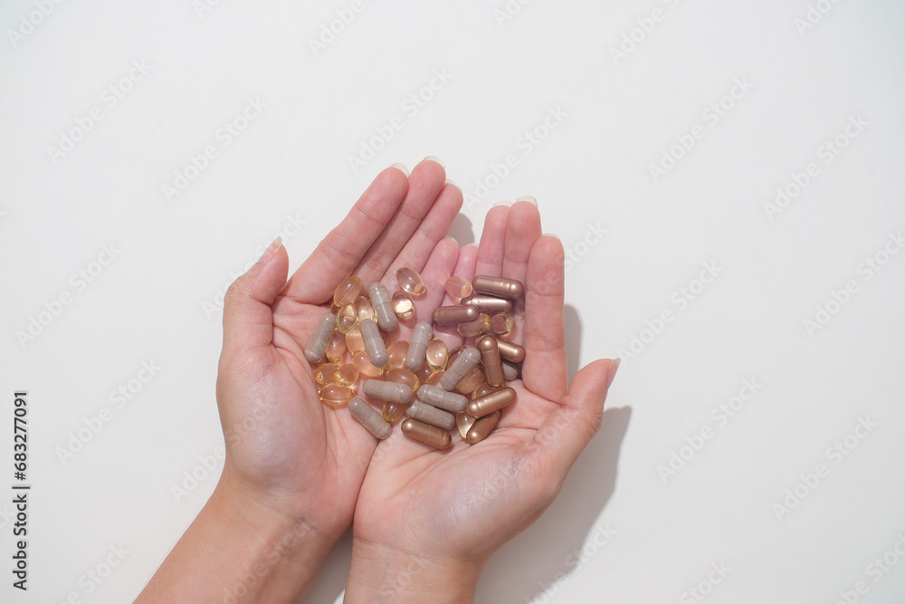 Two hands together holding capsules on white background. Vitamins are ...