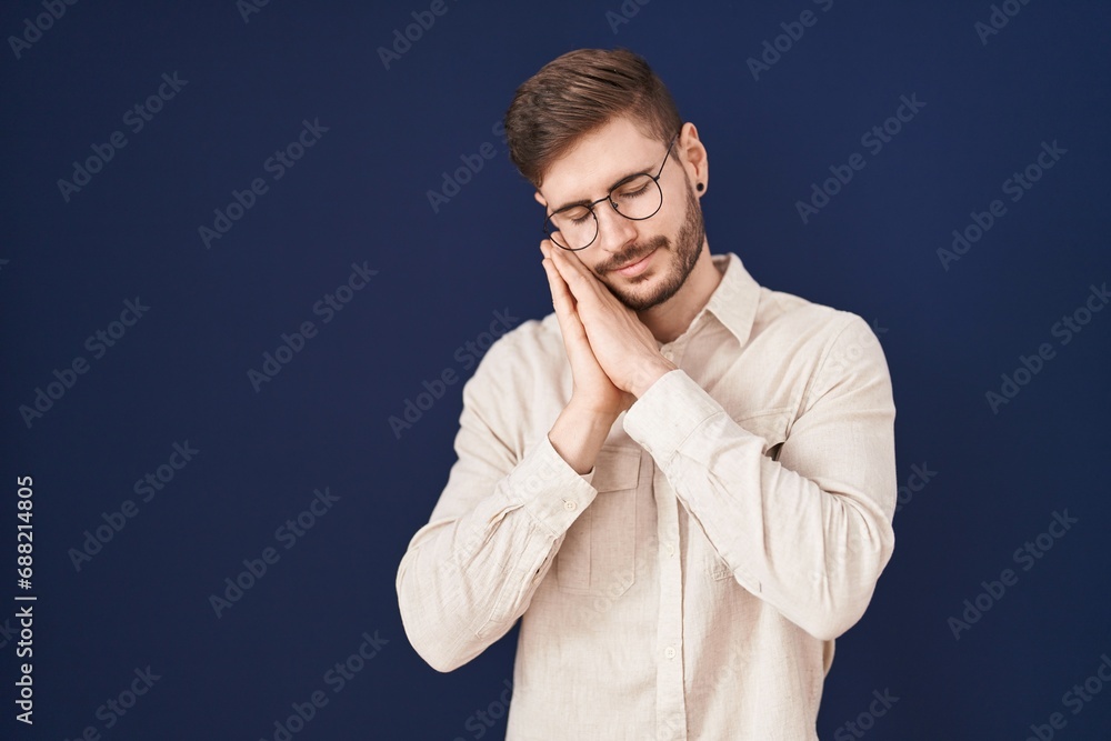 Hispanic man with beard standing over blue background sleeping tired ...
