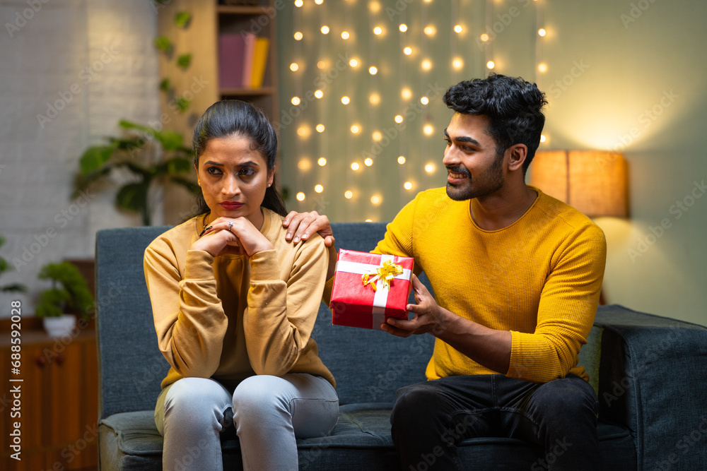 Angry indian girl rejecting gift from boyfriend while sitting on sofa ...