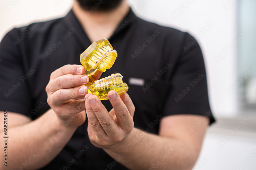 Doctor performing artificial human jaws of yellow plastic with ...