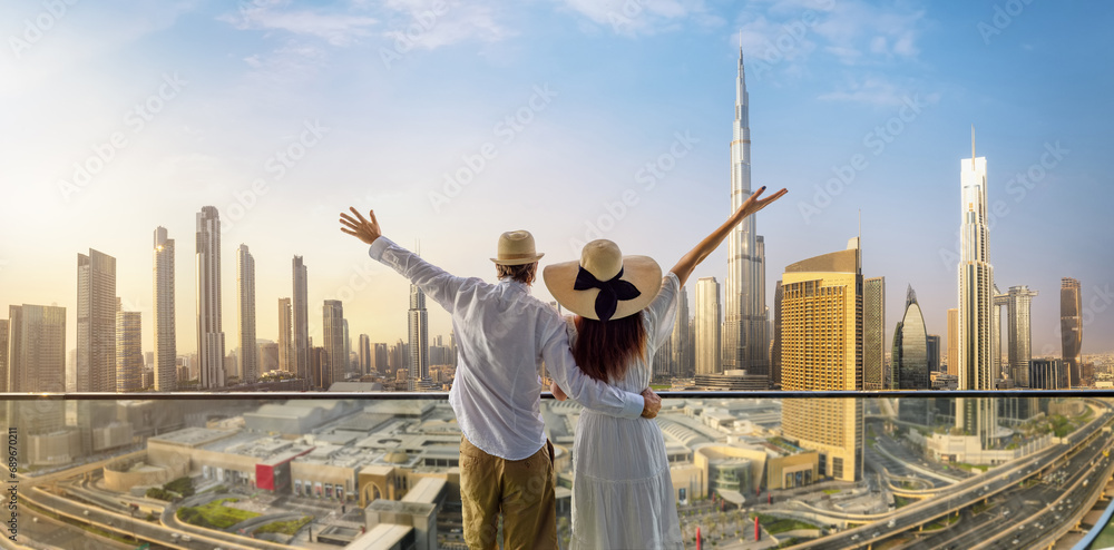 A happy tourist couple on vacation time stands on a balcony and enjoys the panoramic view of the ...