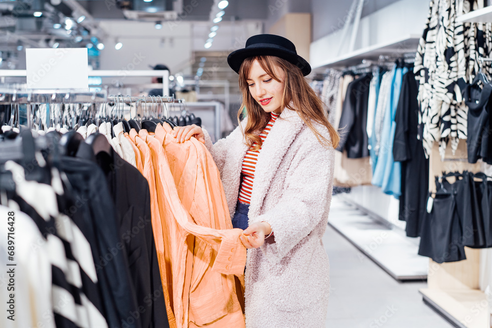 Fashion woman customer looking on peach color shirt in store. Buying ...
