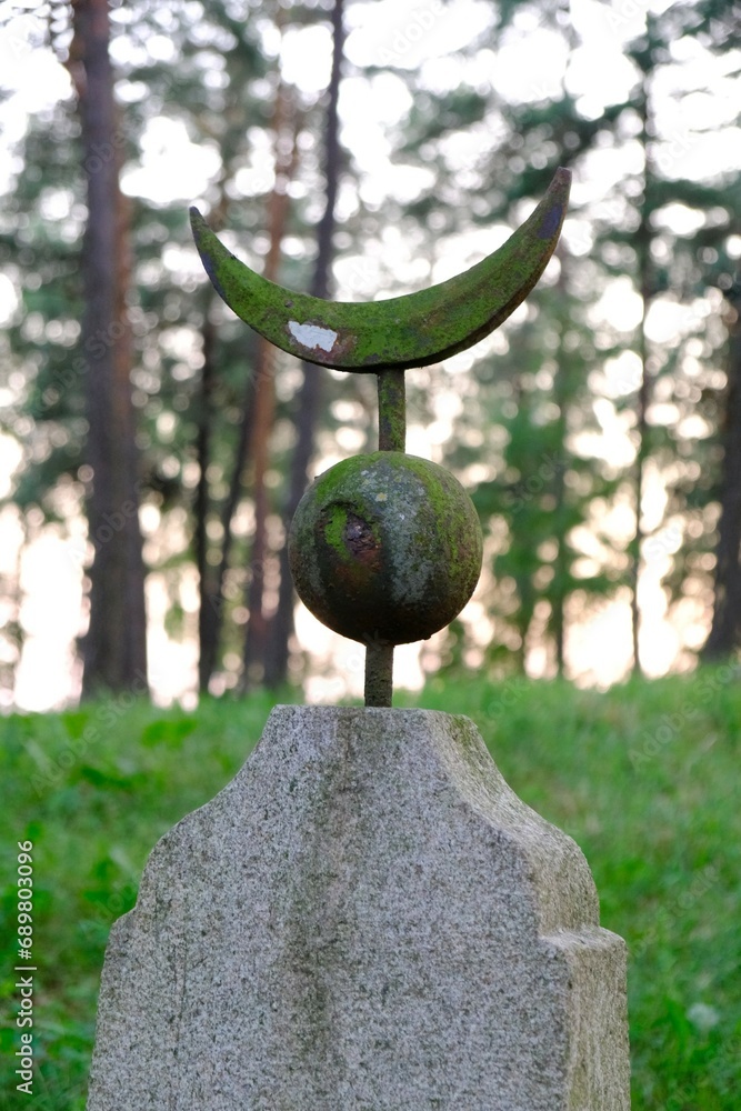 Close up of an old stone tombstone with a metal crescent symbol in the ...