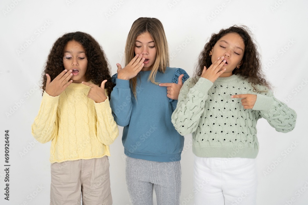 Shocked Three beautiful multiracial kid girls look surprisedly down ...