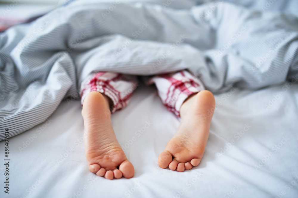 Little child's feet in bed covered with blanket Stock Photo | Adobe Stock