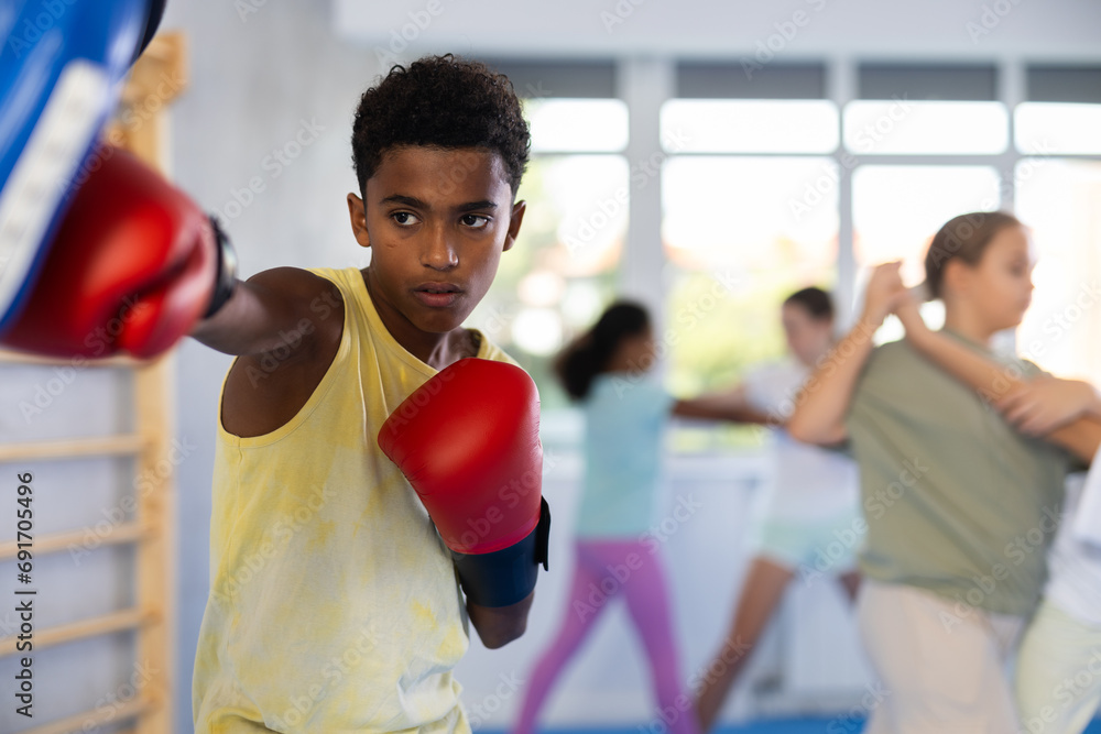 Motivated focused african american boy wearing boxing gloves working ...