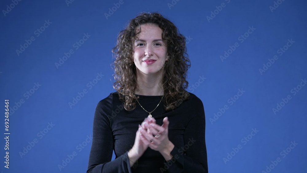 Woman clapping hands congratulating viewer standing on blue background ...