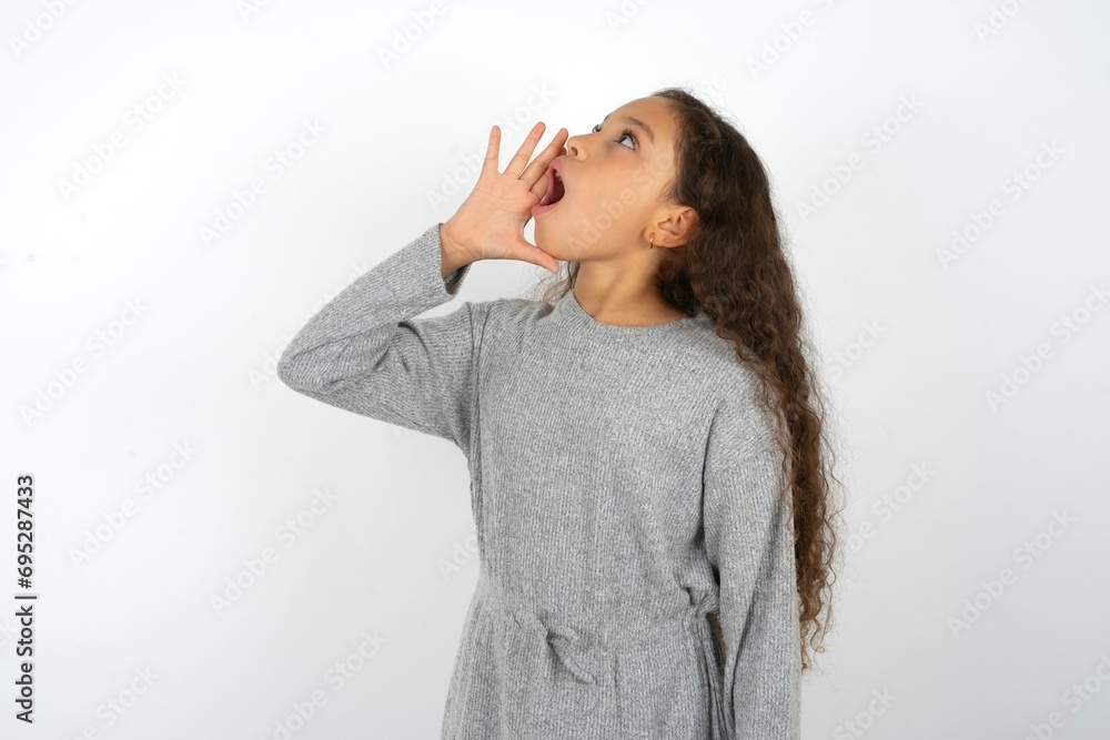 Beautiful teen girl wearing grey dress over white background shouting ...