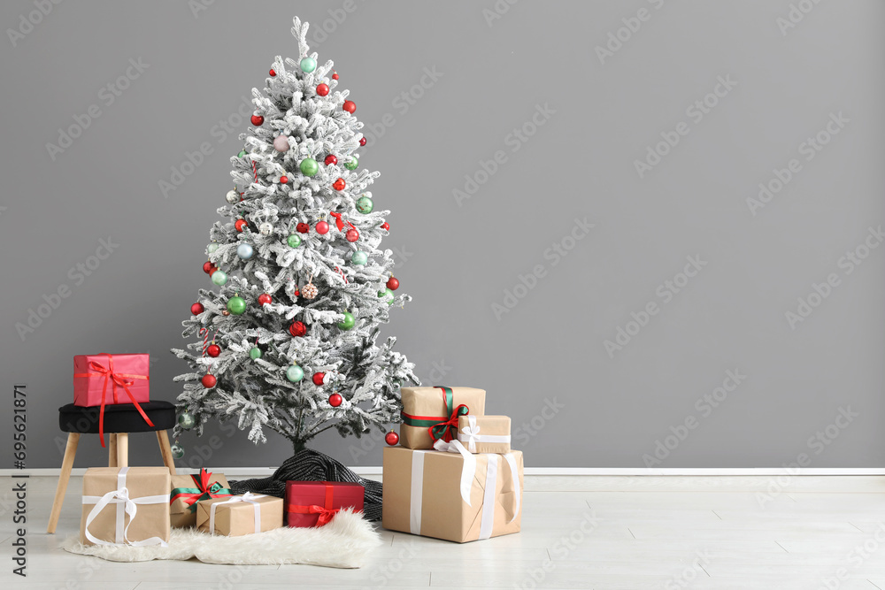 Decorated Christmas tree with gifts and stool against grey wall Stock ...