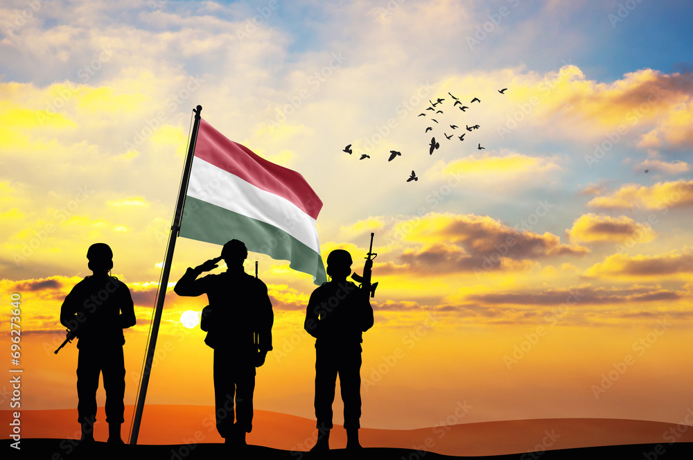 Silhouettes of soldiers with the Hungary flag stand against the ...