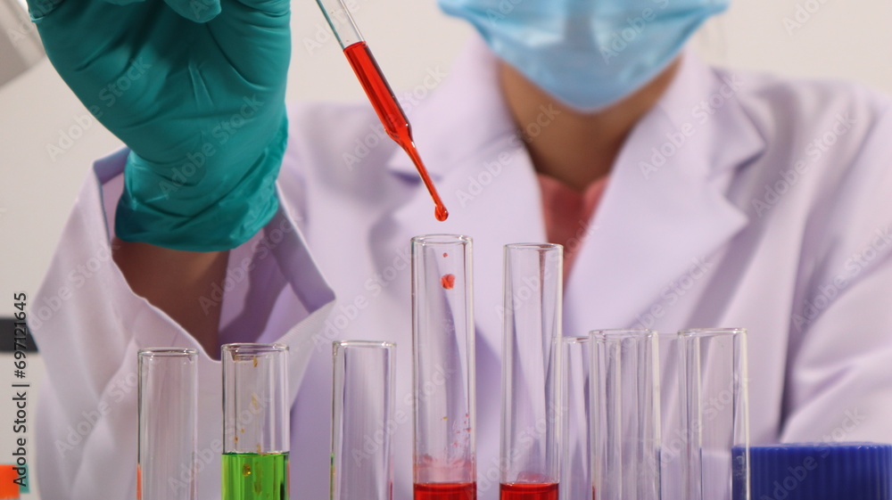 laboratory setting with colorful liquids in test tubes and a person ...