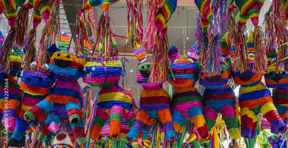 Colorful piñatas of different shapes and sizes hanging over the stalls ...