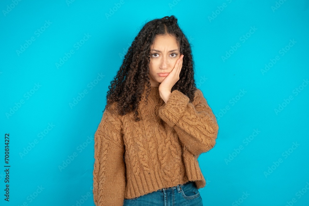 Sad lonely Beautiful teen girl wearing knitted sweater over blue ...