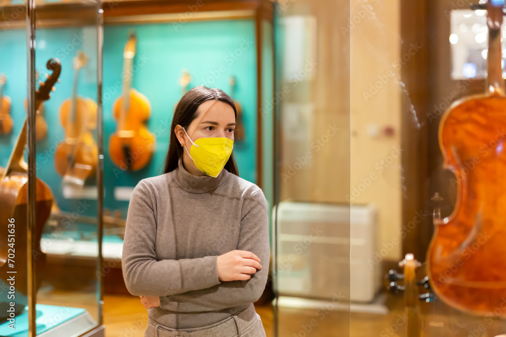 Interested young woman wearing protective face mask viewing collections ...