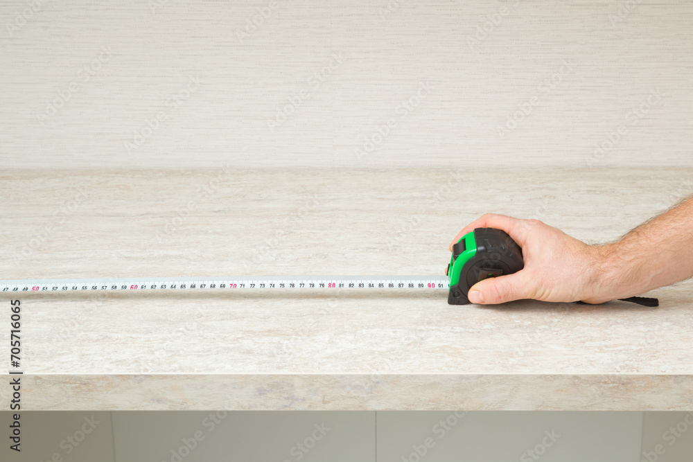 Young adult man hand holding measure tape and measuring surface of ...