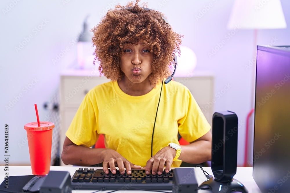 Young hispanic woman with curly hair playing video games wearing ...