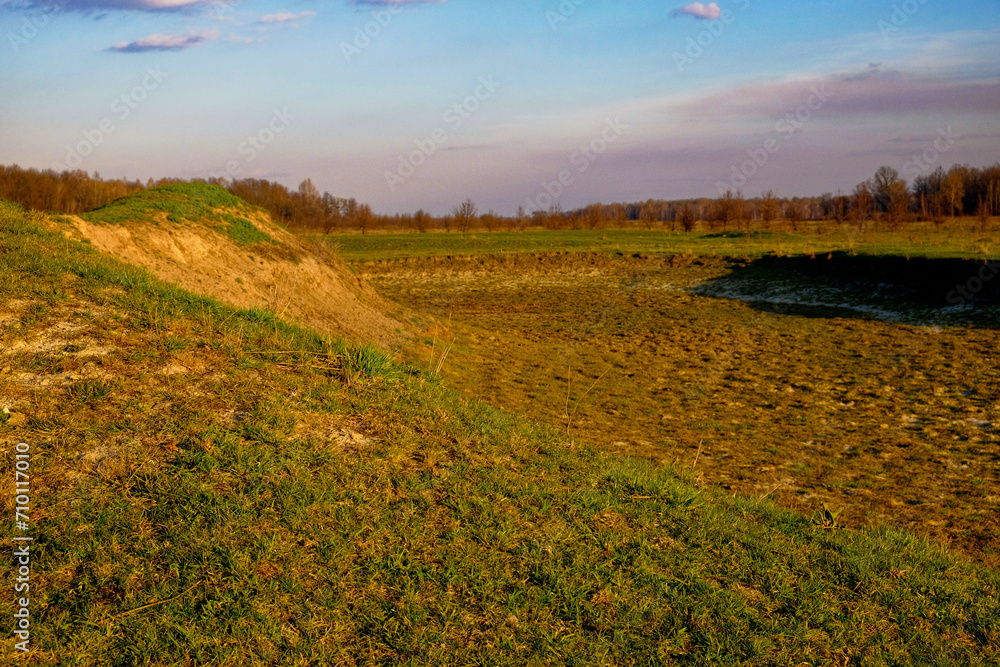 In this scene, the landscape unveils the dry pond's exposed bottom ...