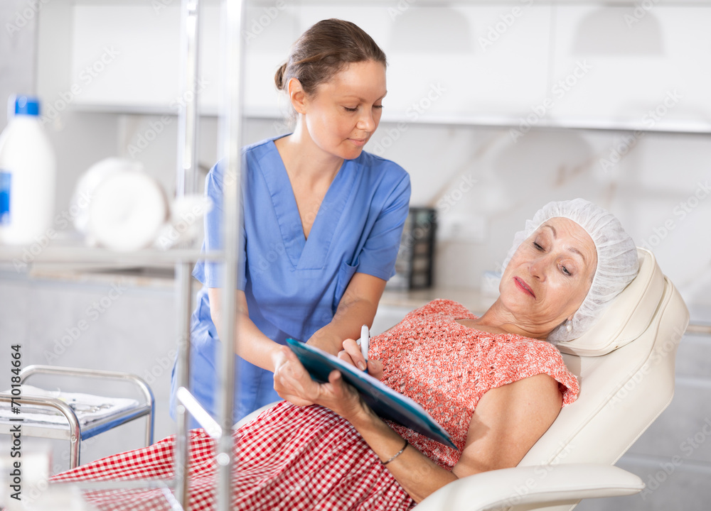 Before medical manipulation, mature woman patient sits in chair and ...