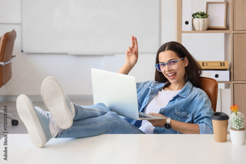 Pretty young female programmer with legs on table resting in office ...