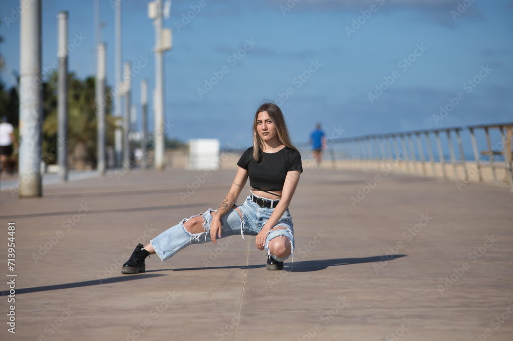 Young, beautiful blonde woman, green eyes, with black top, torn jeans ...