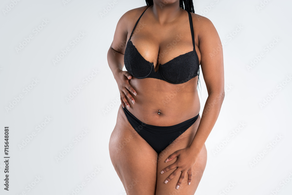 Curvy busty plus size model in push up bra on gray background, overweight African black woman in ...