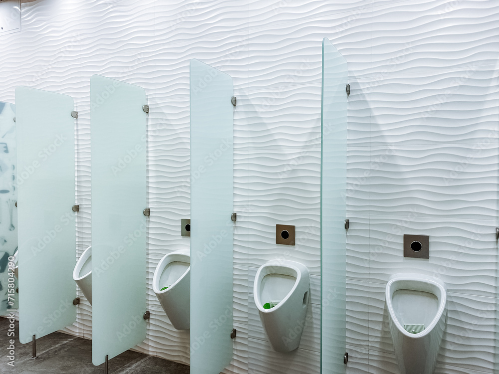An urban urinal in the men's restroom, porcelain trays hanging on the ...