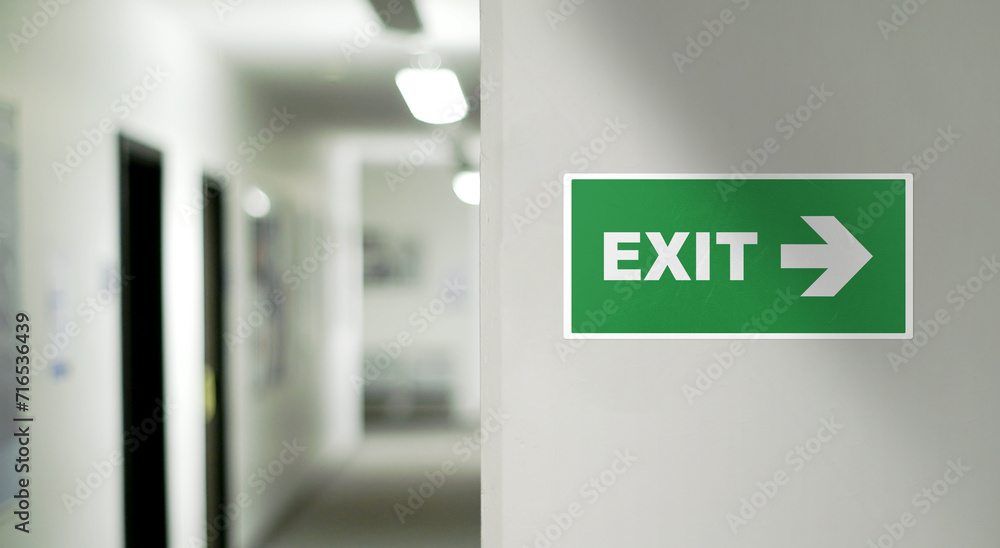 Emergency exit sign on the right with blurred corridor background ...