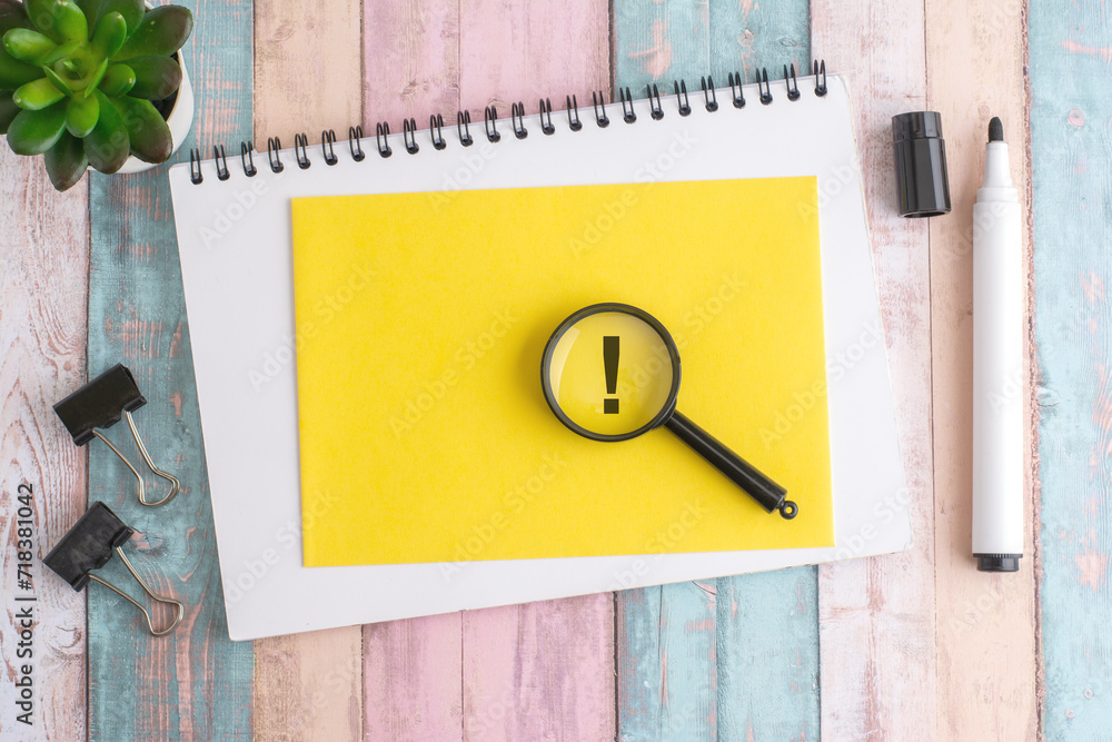 exclamation mark under a magnifying glass on a yellow background, top ...