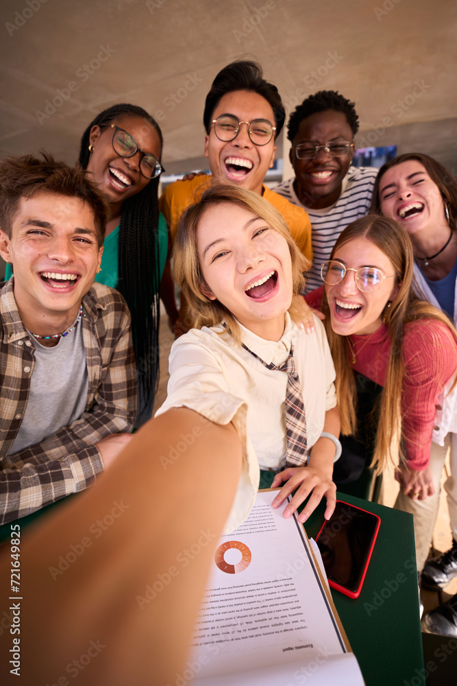 Vertical. Group of smiling and cheerful young multiracial university students taking a selfie ...