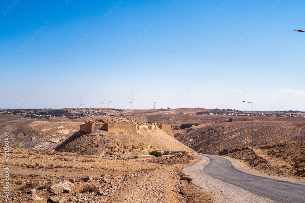 An eroded sandstone & crumbling ruins of.acastle sits on a mound in the ...