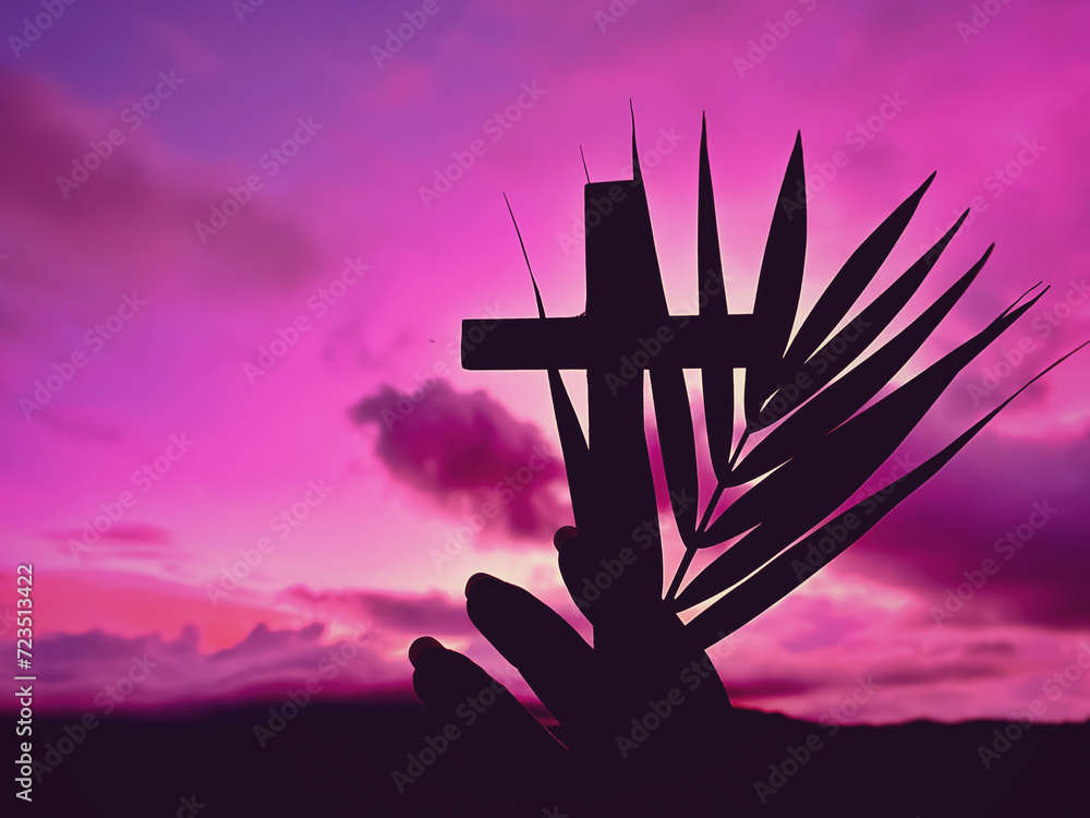 Silhouette of hand holding palm leaves and cross with purple sky ...