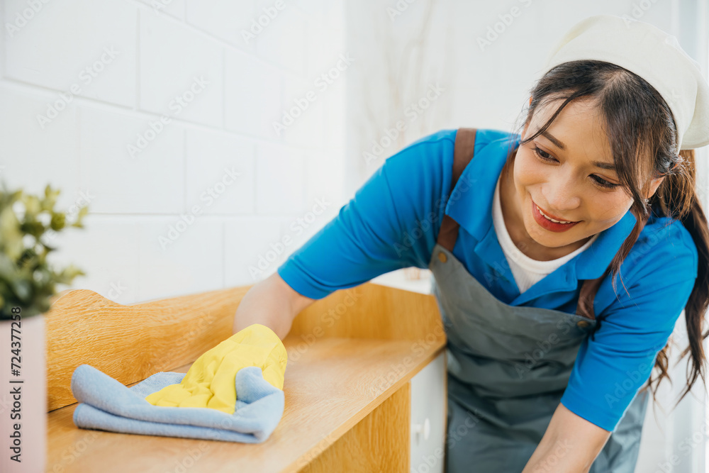 Diligent housewife smiles while wiping table with care in her living ...