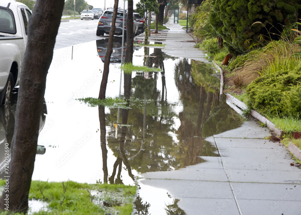 Sidewalk and side of road with standing water, flooded after heavy rain ...