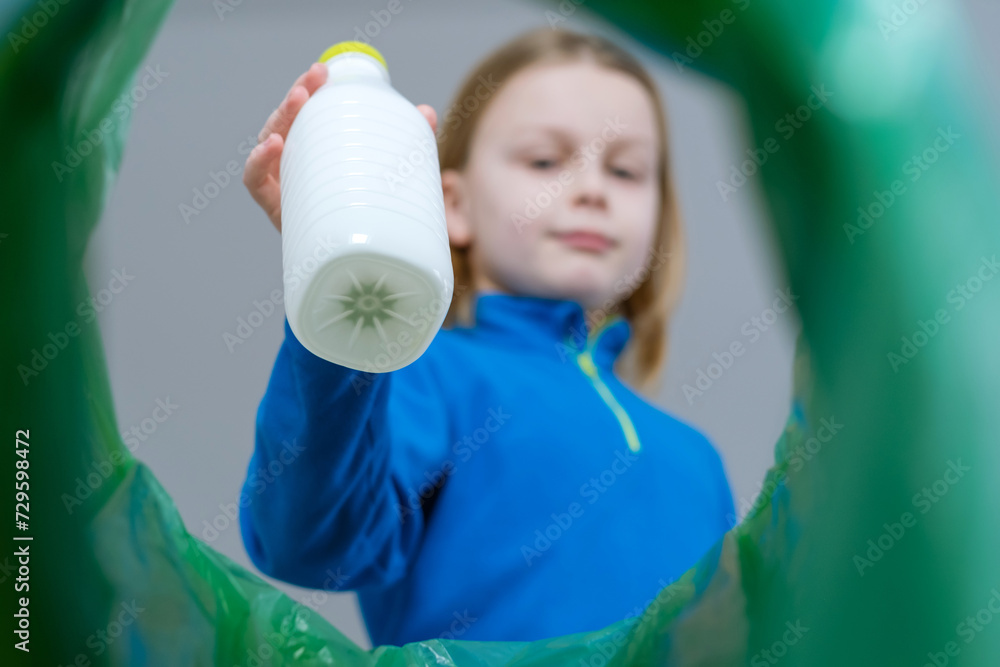 Portrait of a child with a collection of plastic milk bottles. Waste ...