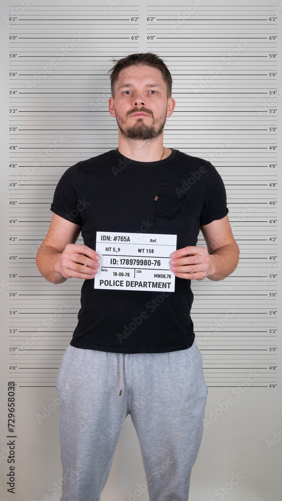 Brunette caucasian man standing with criminal mugshot letter board at ...