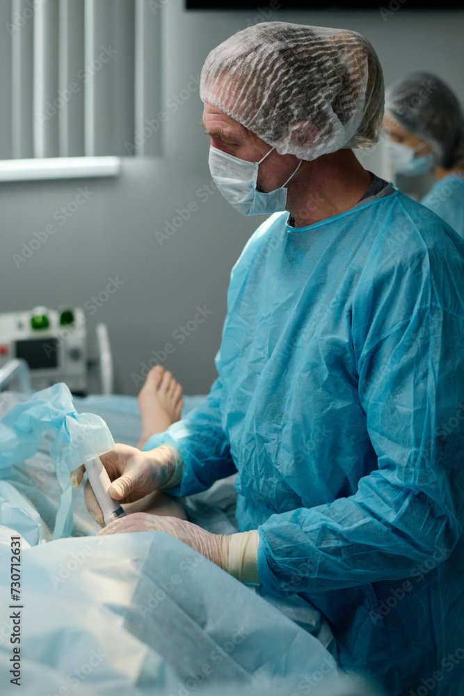 Experienced male clinician with probe standing by operating table with ...