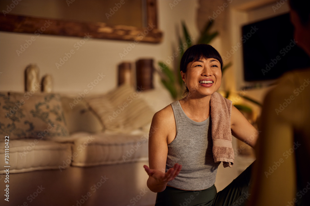 Focus on the smiling Asian yoga instructor, sitting on the floor ...