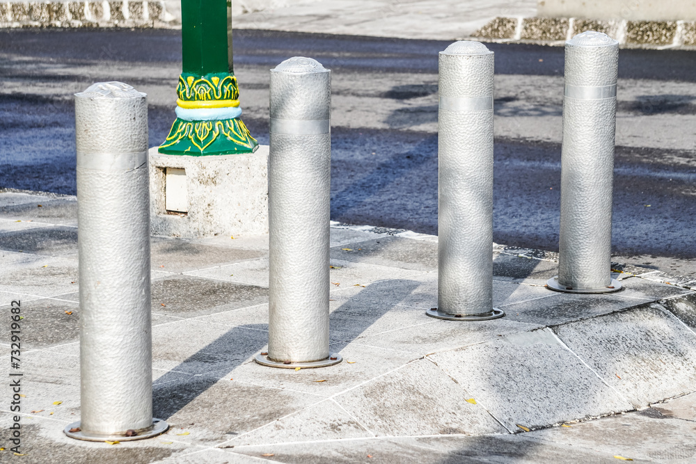 Metallic long inground bollard pole barrier between asphalt road and ...