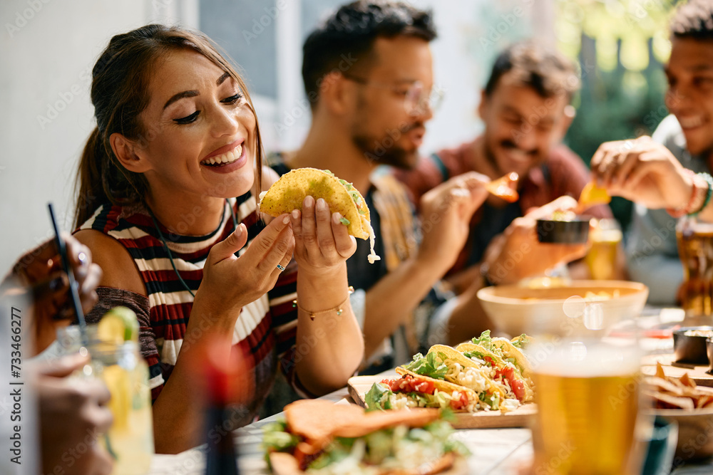 Happy woman eating tacos during lunch with friends in Mexican ...