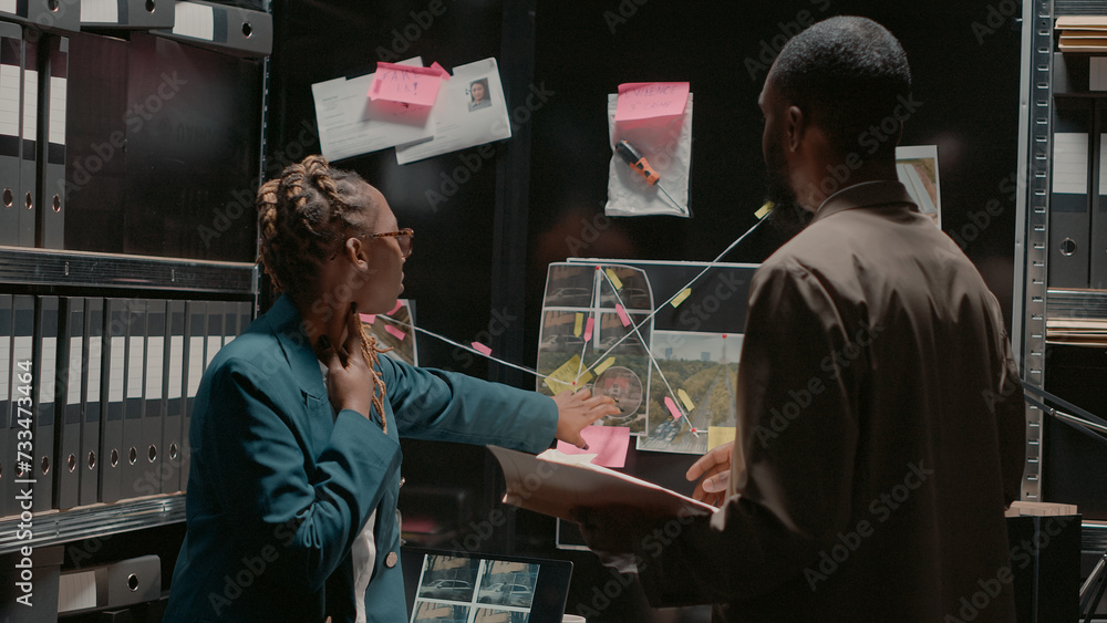 Detective partners analyzing criminal records in office, looking at ...
