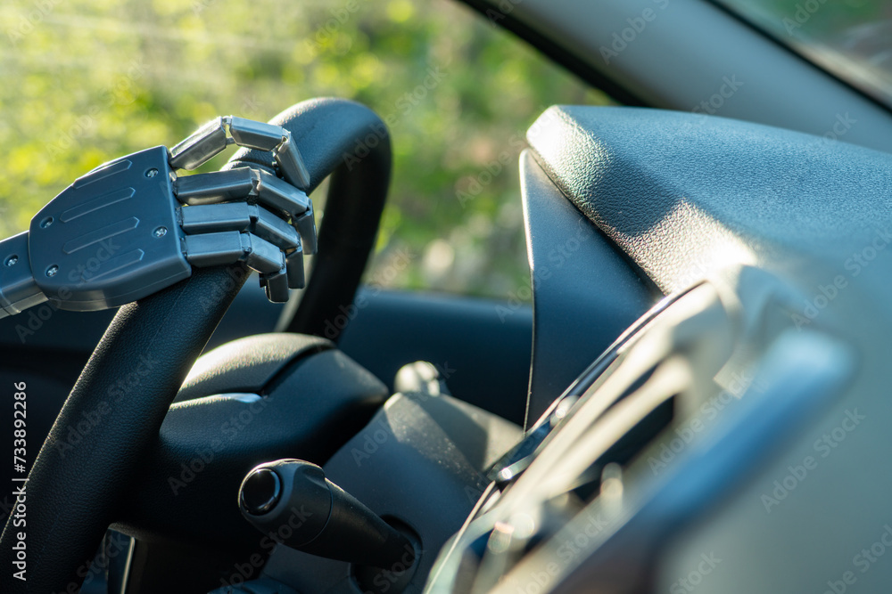 Robot arm on a steering wheel. Artificial intelligence drives a car ...