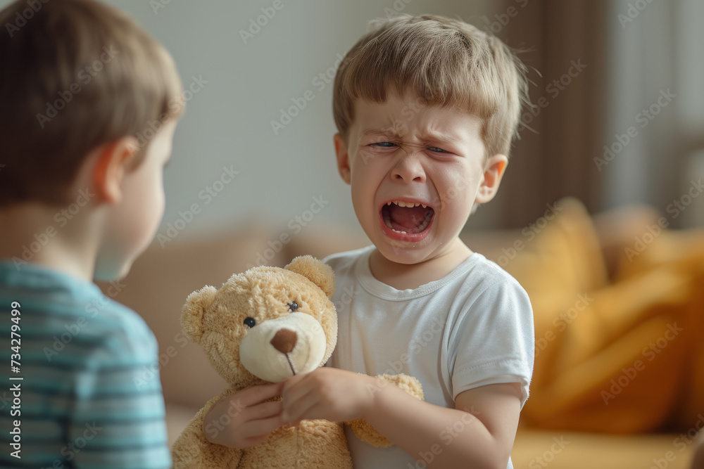 child refusing to share his toys with his sibling. He is holding onto ...