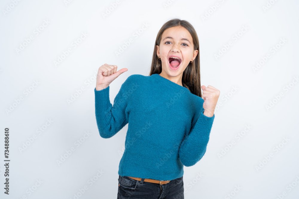 Ecstatic beautiful kid girl wearing blue sweater shout loud yeah fist ...