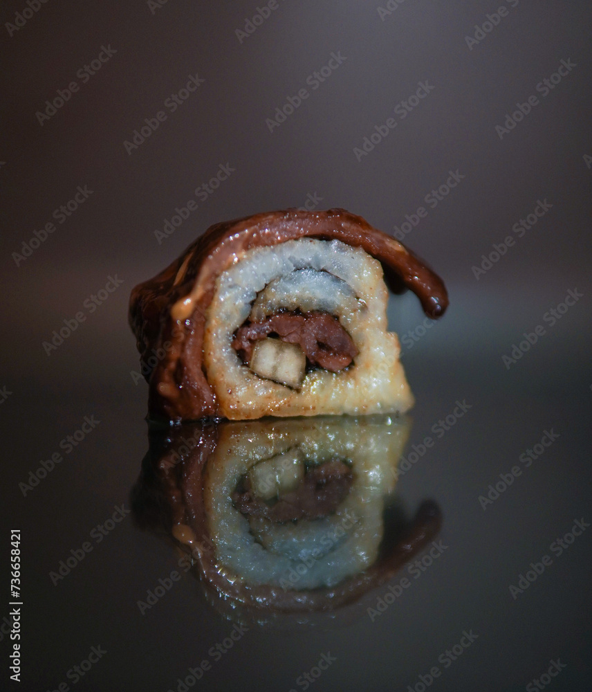 Beef teriyaki roll served on a black wooden plate, avocado, cucumber ...