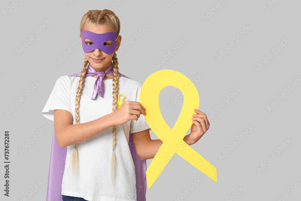 Cute teenage girl in superhero costume with yellow ribbon on grey ...