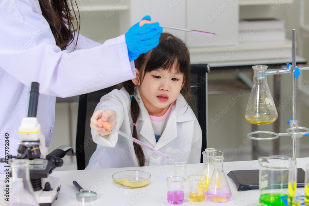 Asian woman scientist and little girl looking through magnifying glass ...