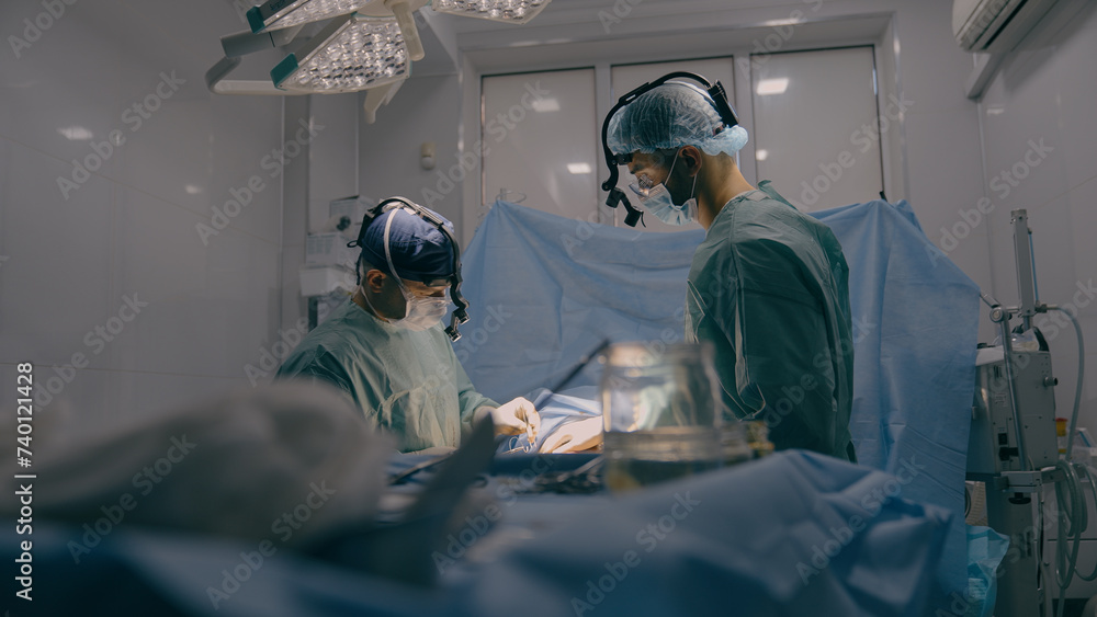 Team of two doctors men surgeons processing surgical operation using ...