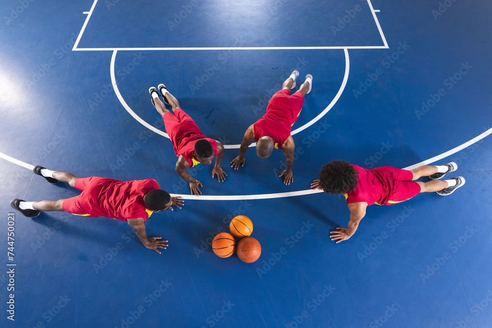 African American and biracial men doing push-ups on a basketball court ...