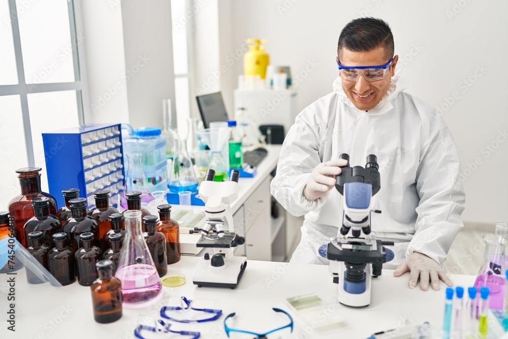 Young latin man scientist wearing covid protection uniform using ...