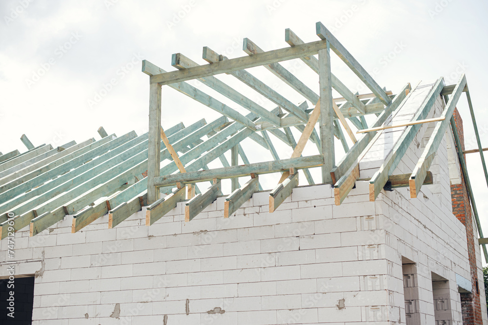 Unfinished modern farmhouse building. Wooden roof framing of mansard ...